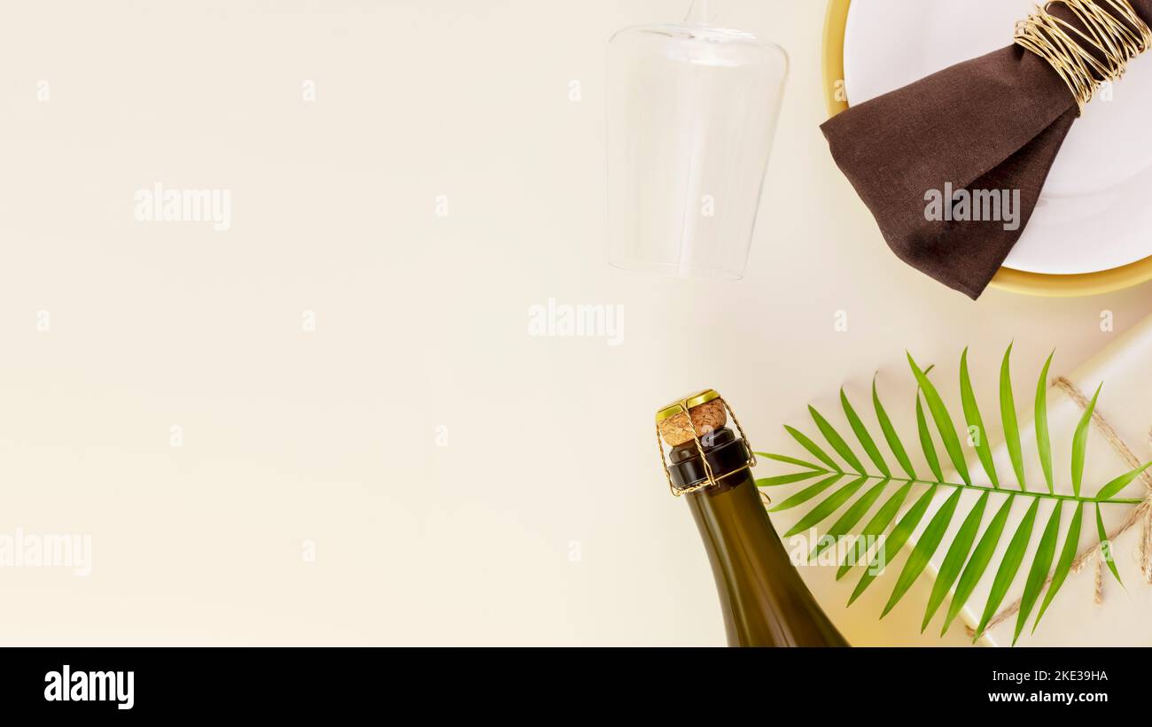 Holiday table setting. Present with palm leaf, bottle of champagne and ...