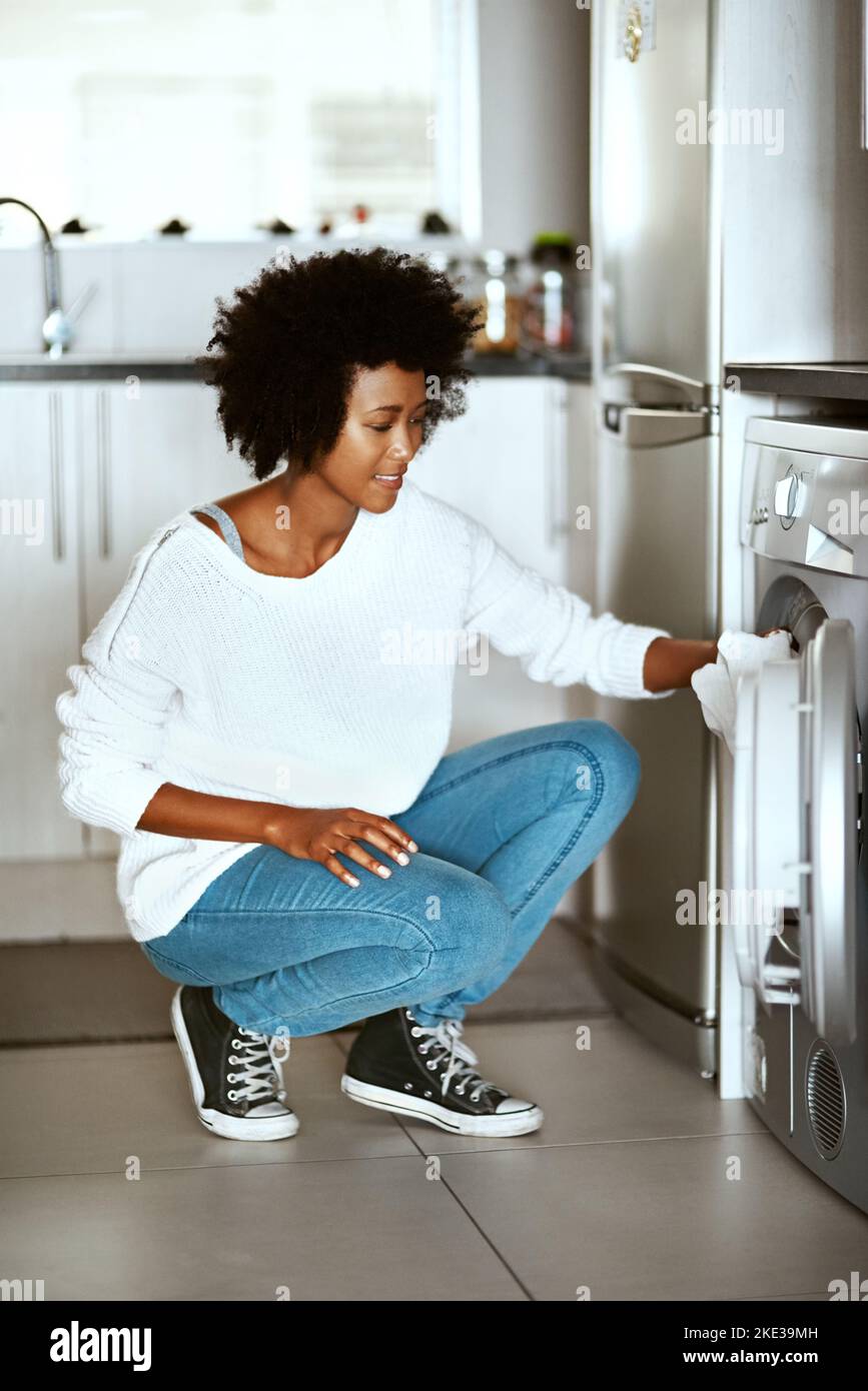 Because who has time to hand wash. a young woman doing laundry at home ...