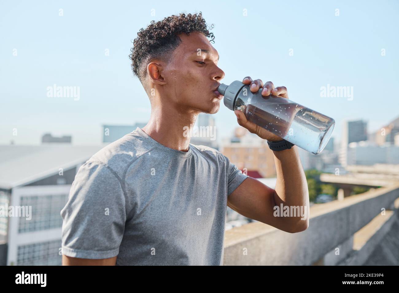 Fitness, exercise and man drinking water in city after running ...