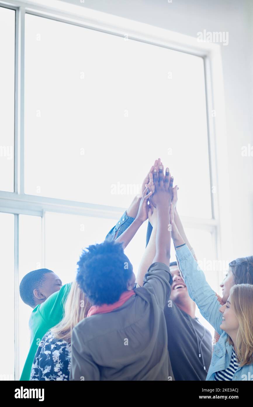 Lets do this. a group of university students high fiving one another ...