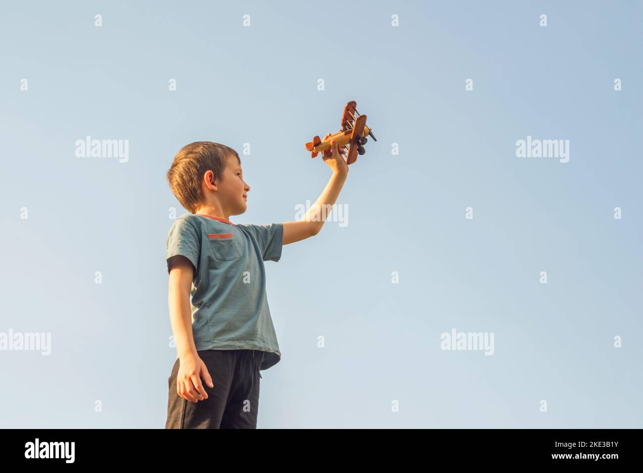 Happy kid playing with toy wooden airplane against sky background Stock ...