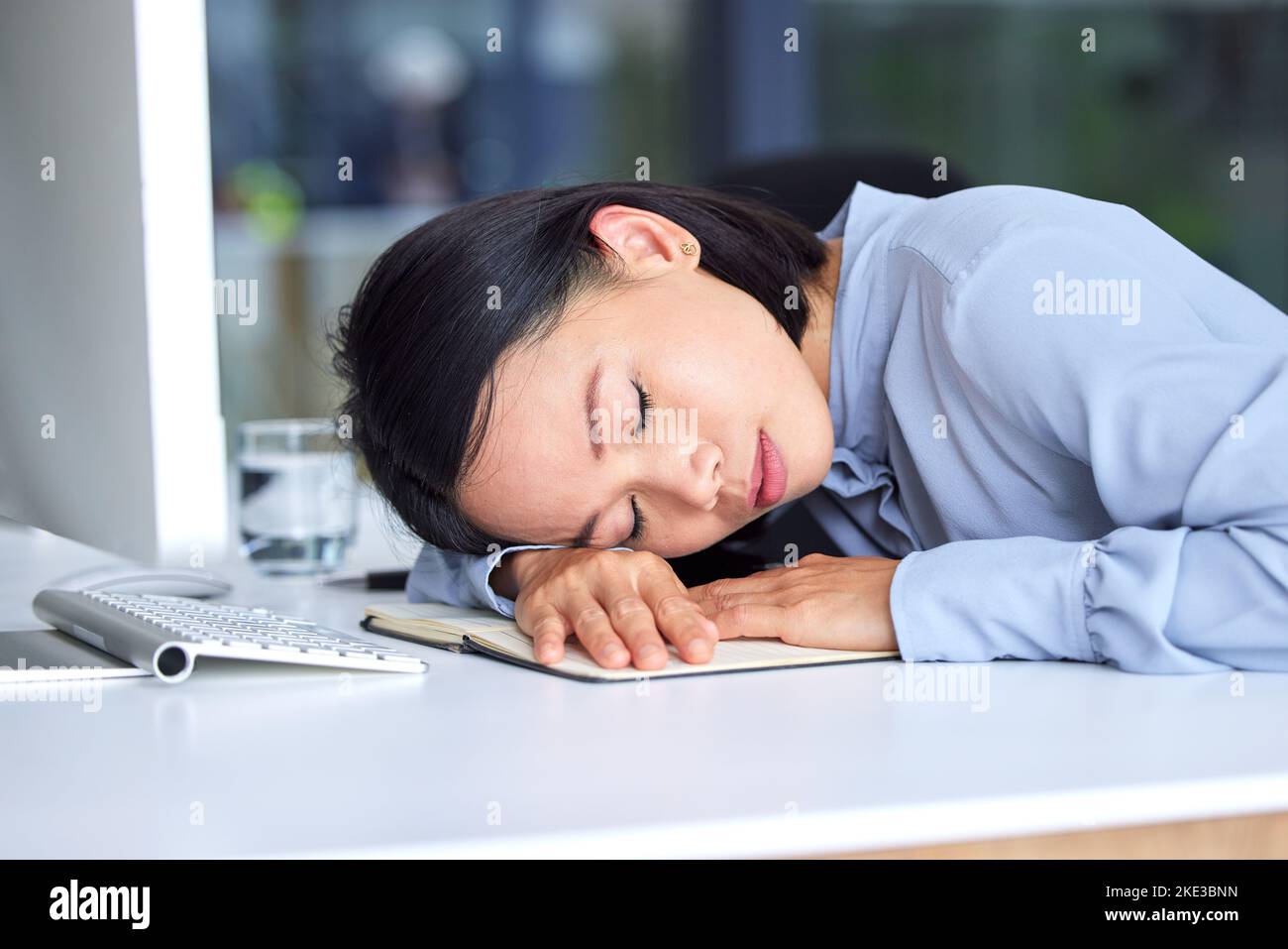 Burnout, tired and business woman sleeping on the desk in her modern ...