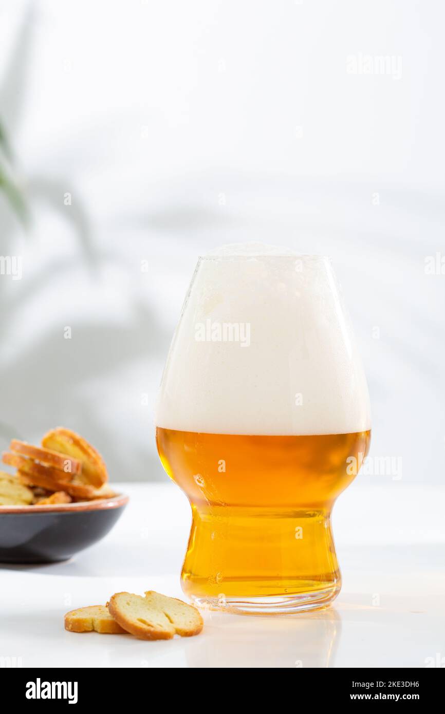One glass with light craft beer snack food and drink on light surface ...