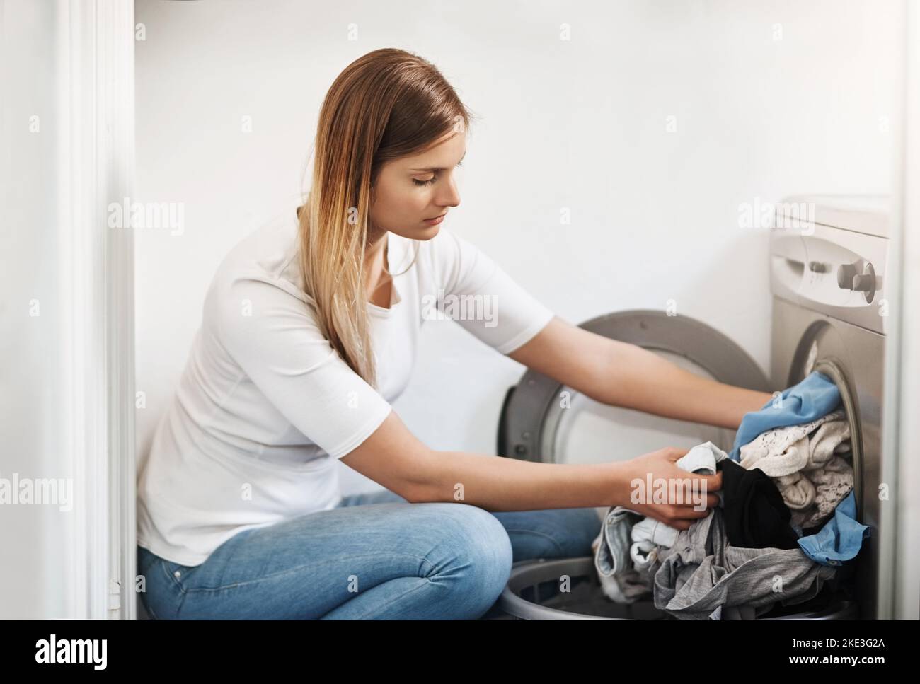 Getting the laundry done. an attractive young woman doing laundry at home Stock Photo - Alamy