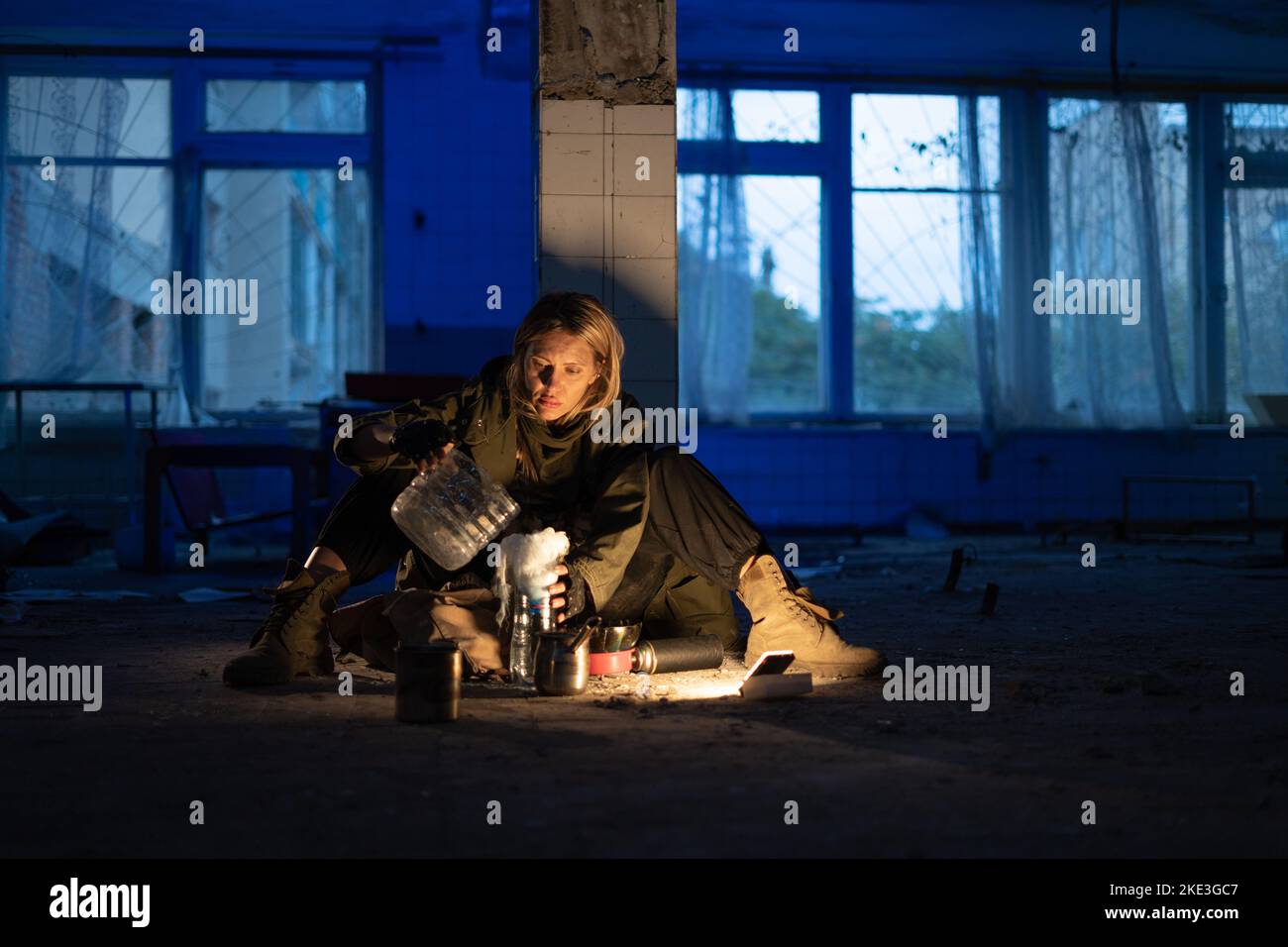 Post-apocalypse. a young woman sits on the floor of an abandoned ...