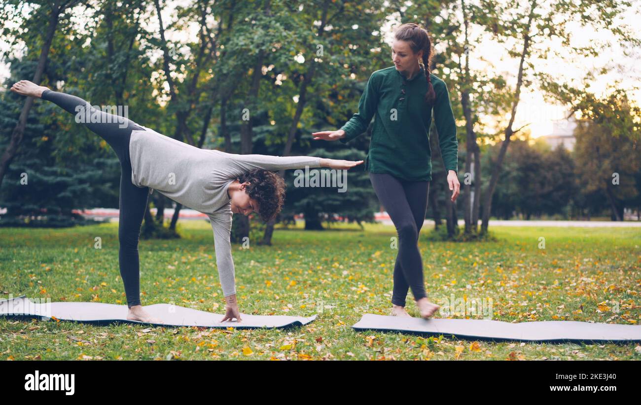 Friendly yoga instructor professional is helping female student to ...