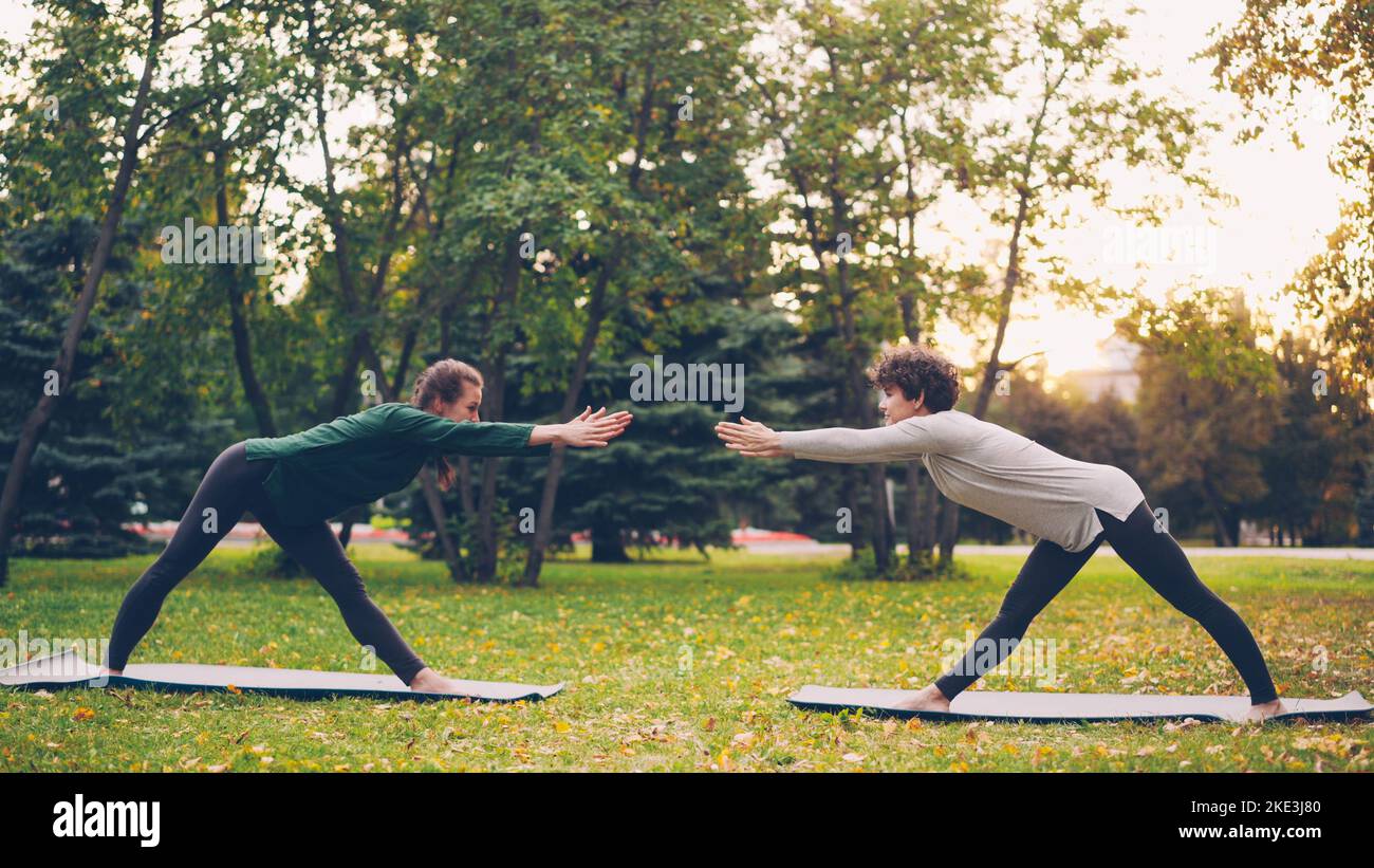 Attractive girls are enjoying outdoor yoga in city park practising ...