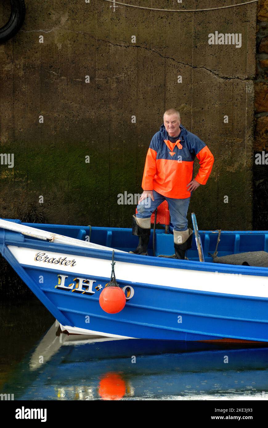 Fisherman in traditional Coble boat, Beadnell harbour, Northumberland ...