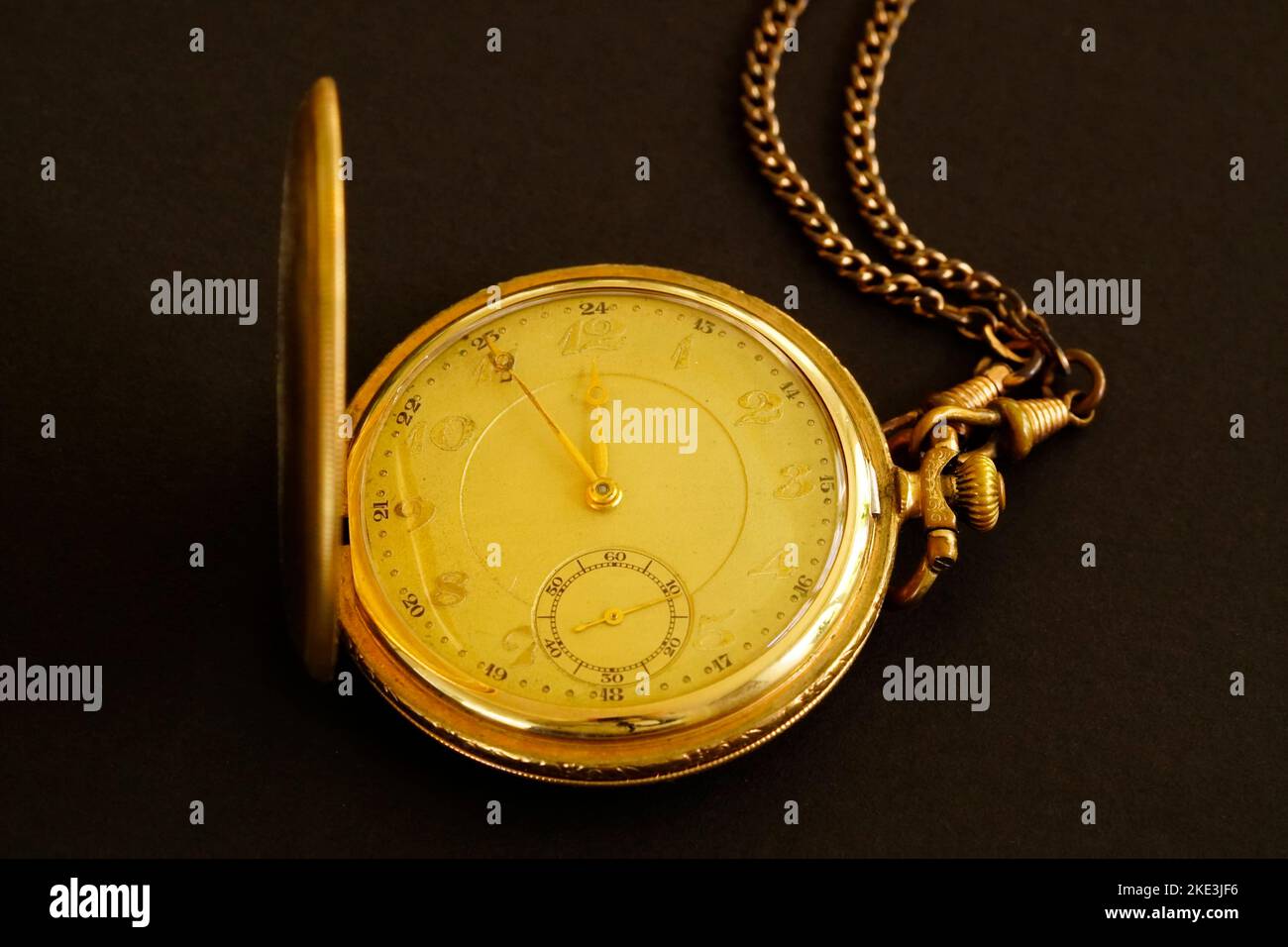Old gold plated pocket watch against a black background Stock Photo - Alamy