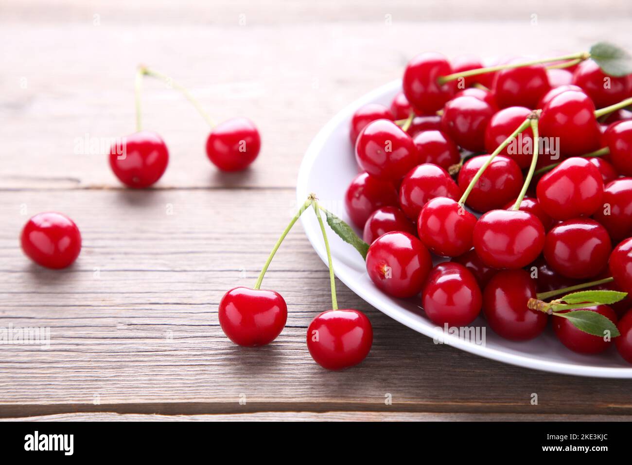 Fresh red cherry fruit in plate on wooden background Stock Photo - Alamy