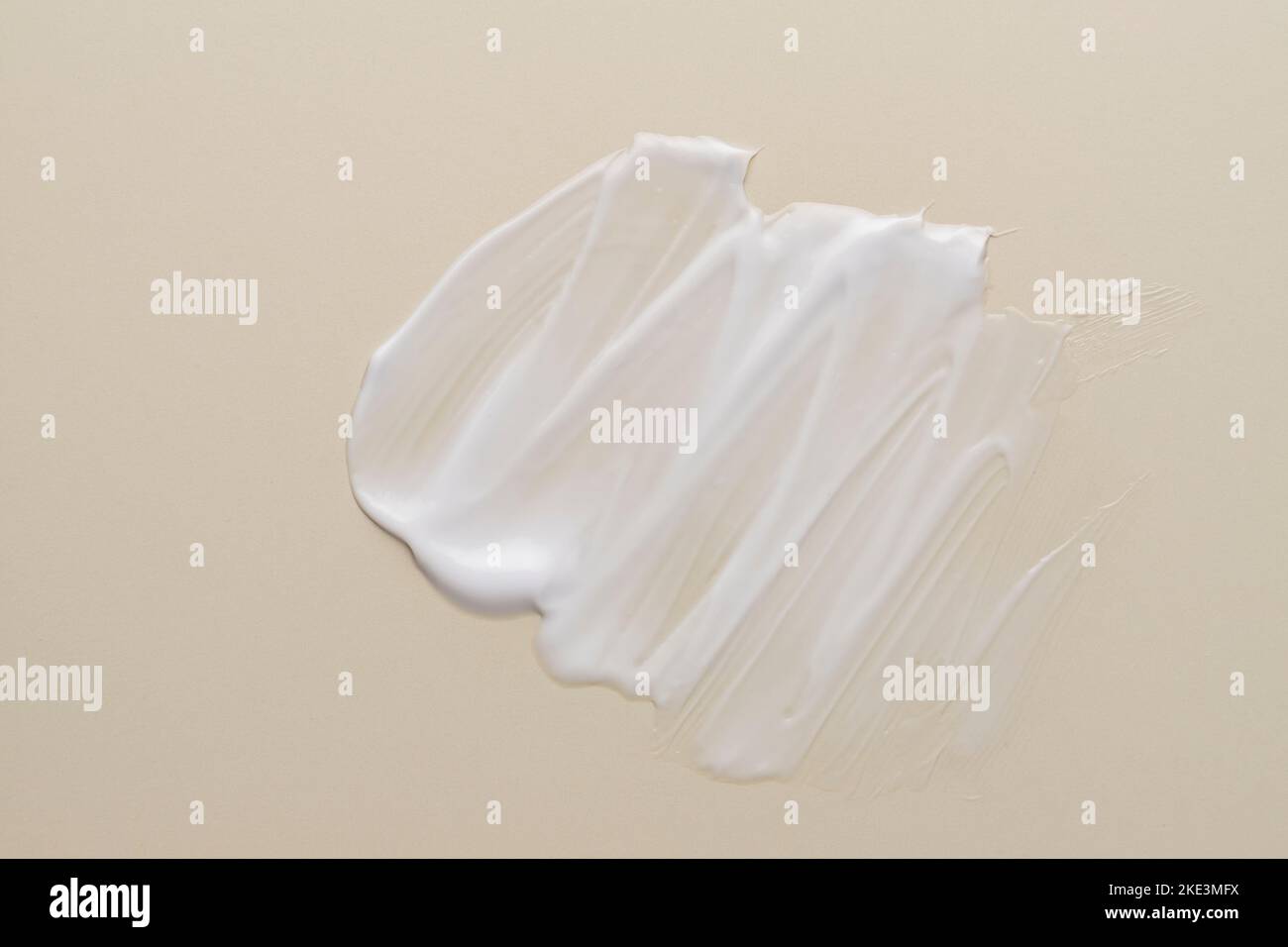 Texture of white cream on beige background. Smear of moisturizer close ...