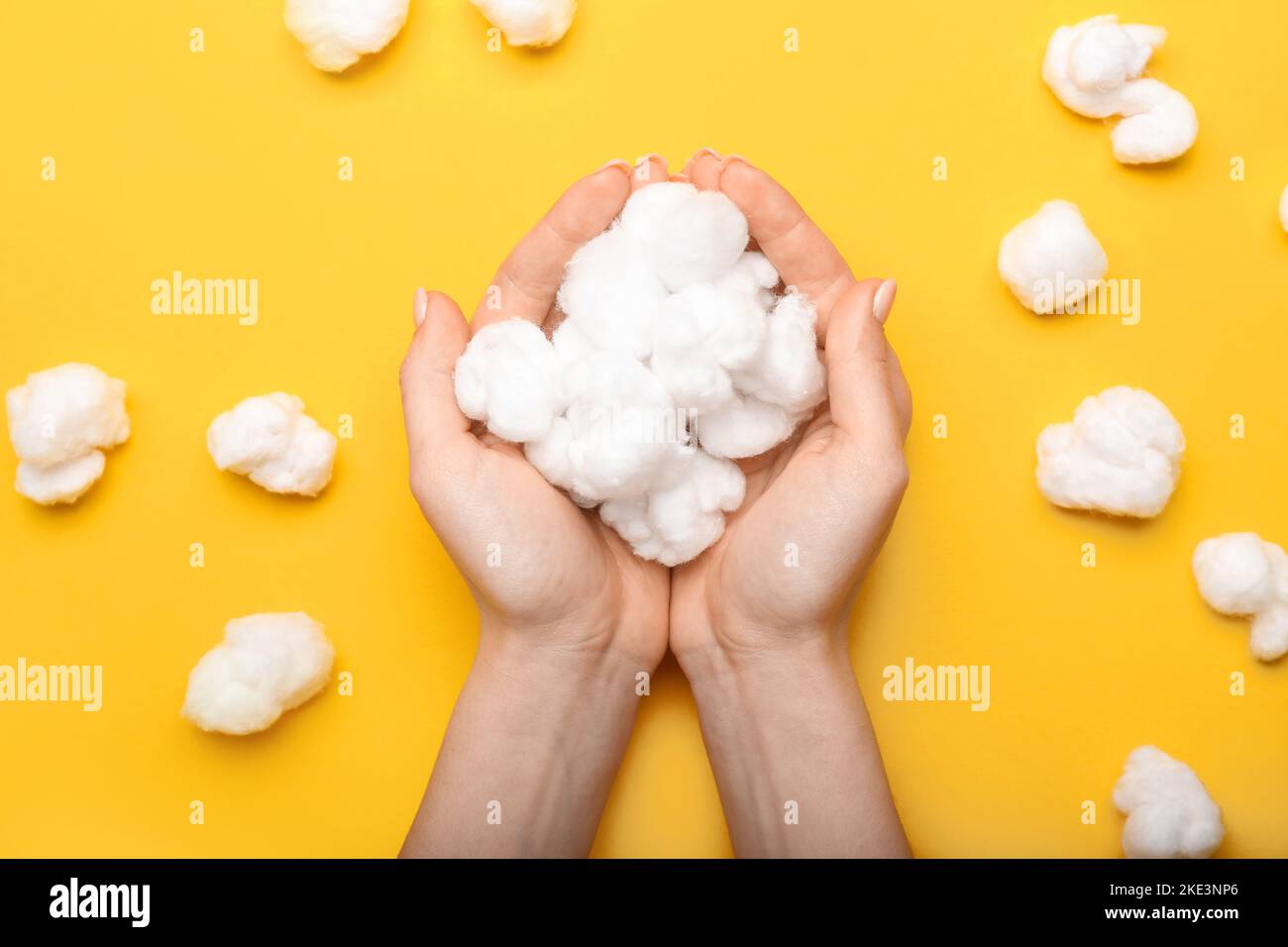 Woman holding soft cotton wool on yellow background Stock Photo - Alamy