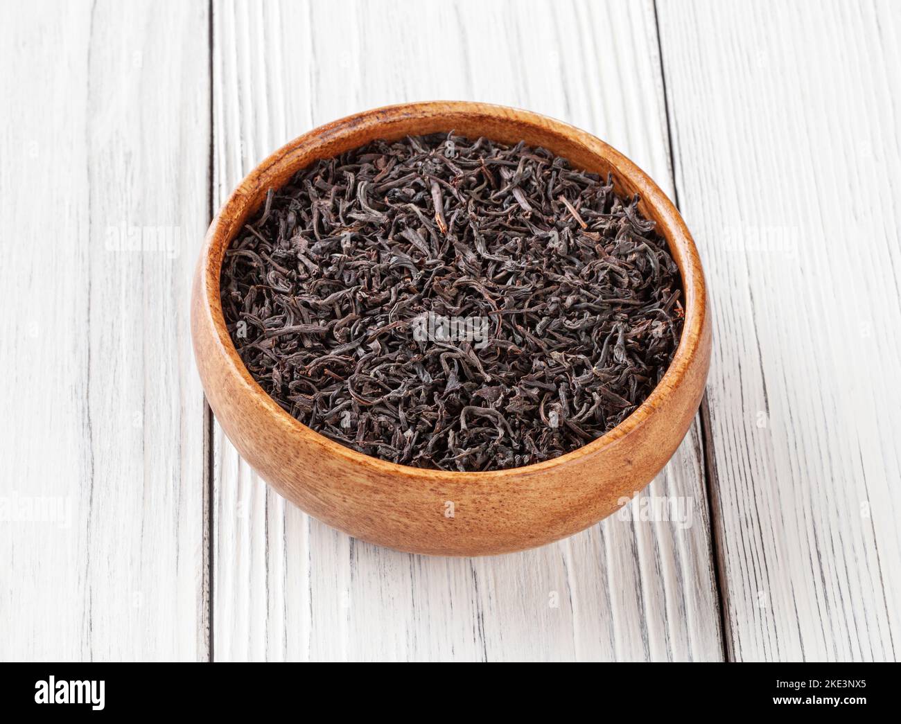Dry black tea in wooden bowl on white wooden background Stock Photo - Alamy