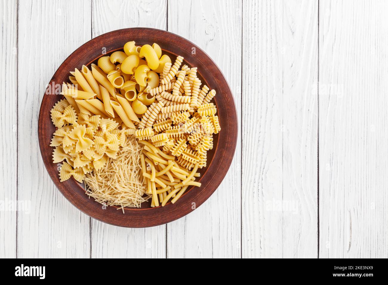 Different types and shapes of Italian pasta in ceramic plate on white ...