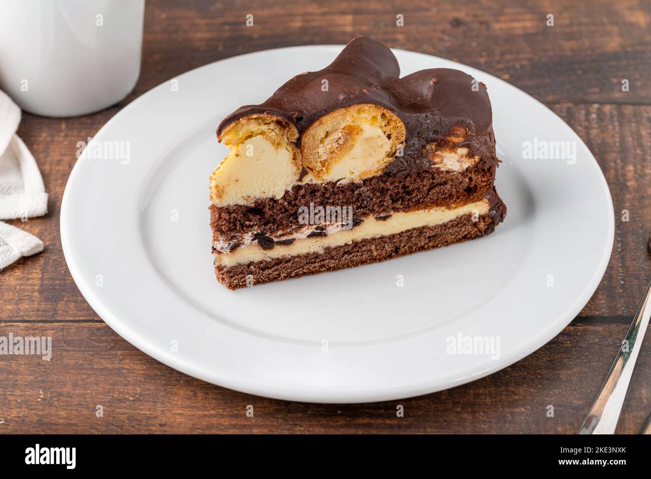 Cake with profiteroles on a white porcelain plate with filter coffee on ...