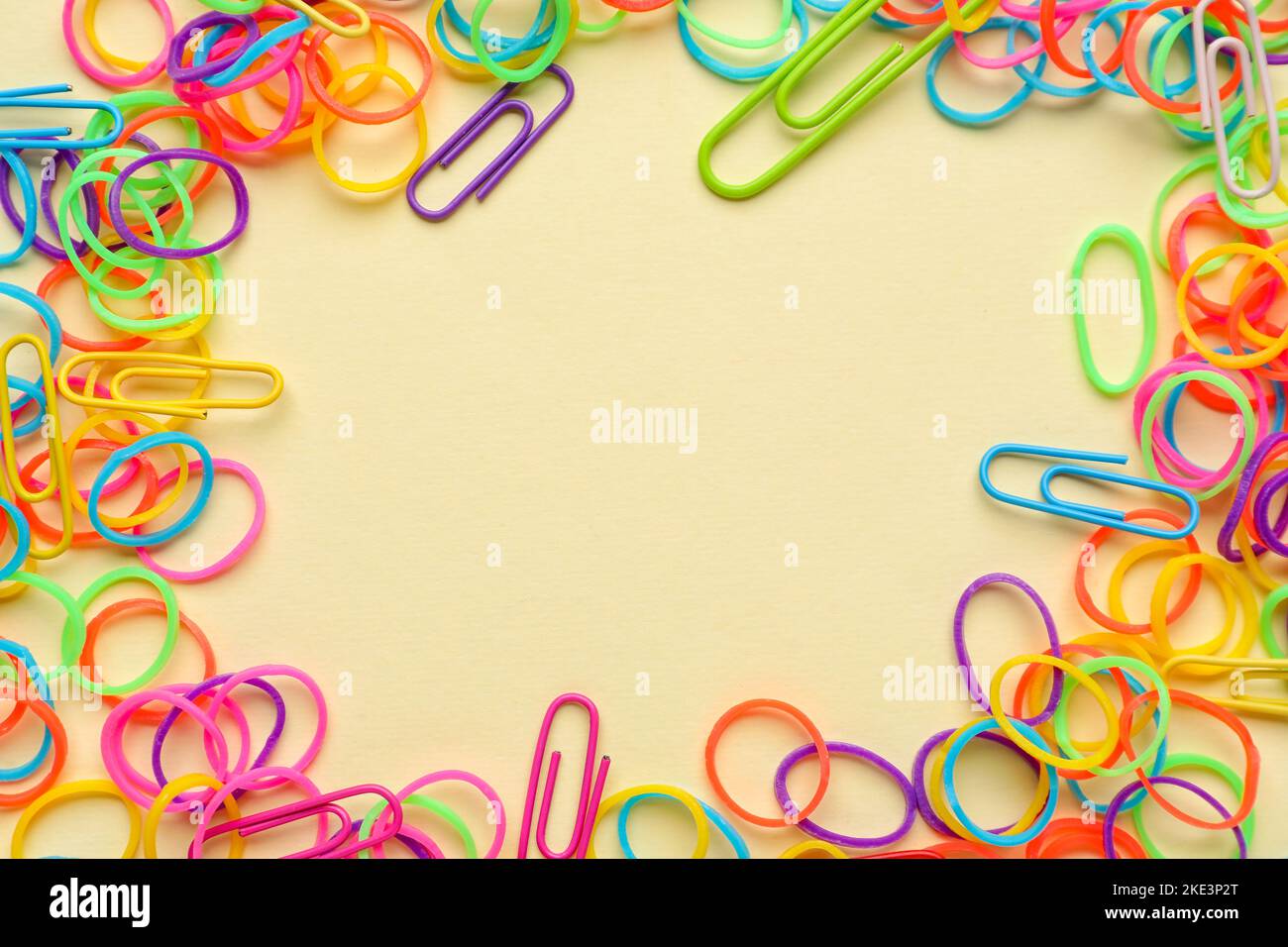 Frame made of colorful rubber bands and paper clips on color background ...