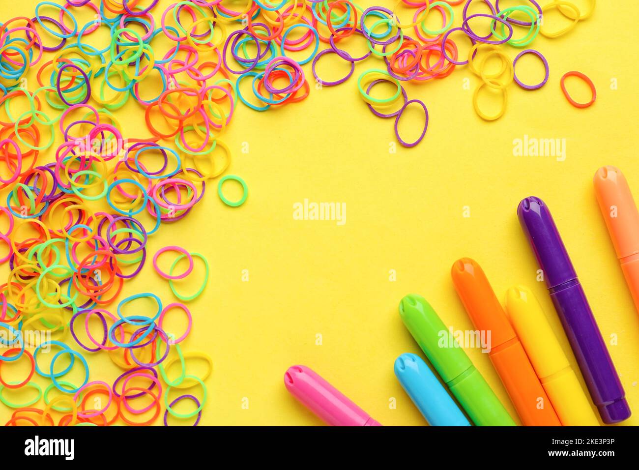 Colorful rubber bands and markers on yellow background Stock Photo - Alamy
