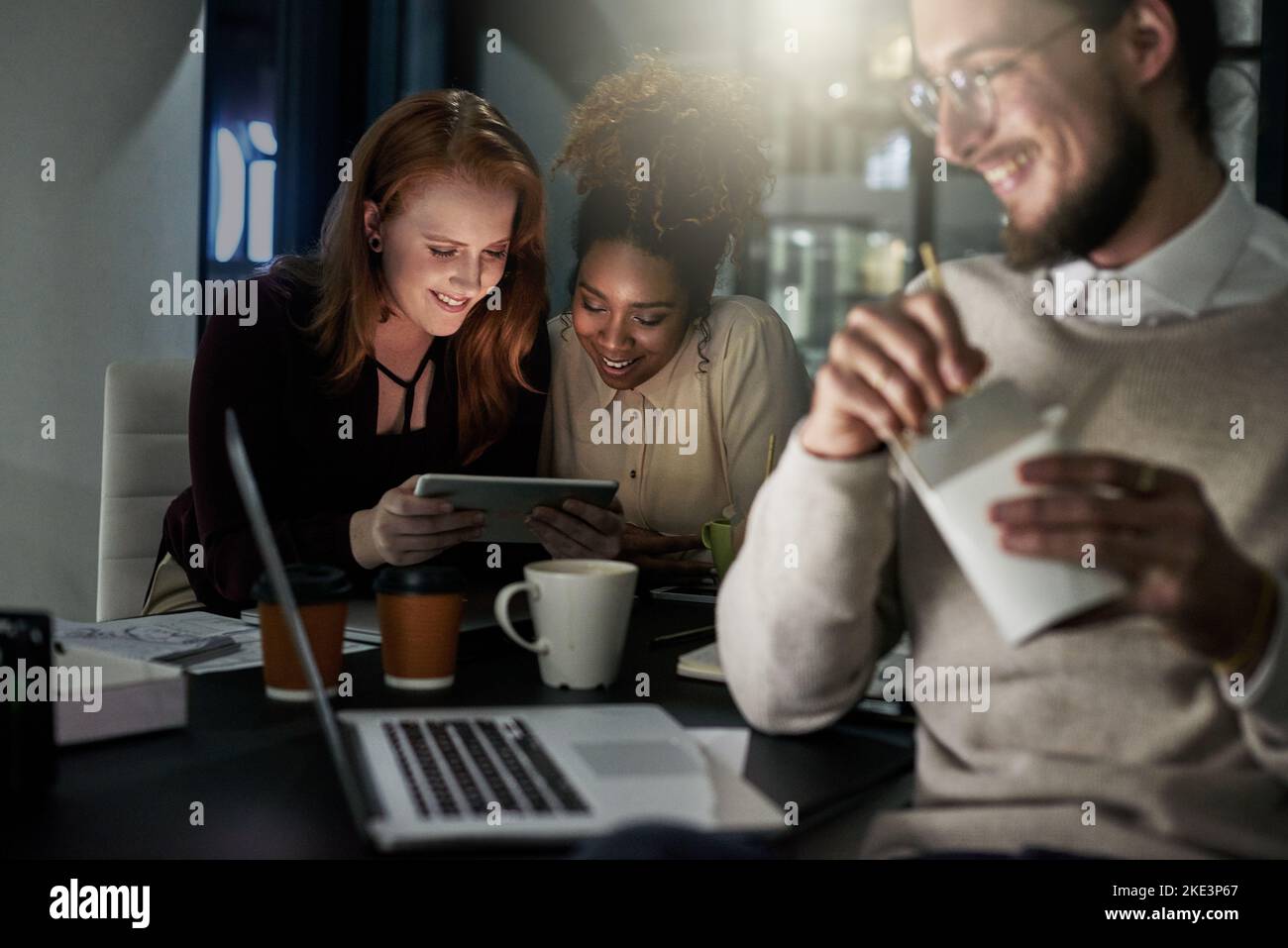 Late nights in the office are a part of the job. a group of young ...