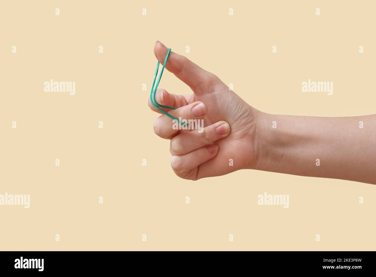 Woman with green rubber band on beige background Stock Photo - Alamy