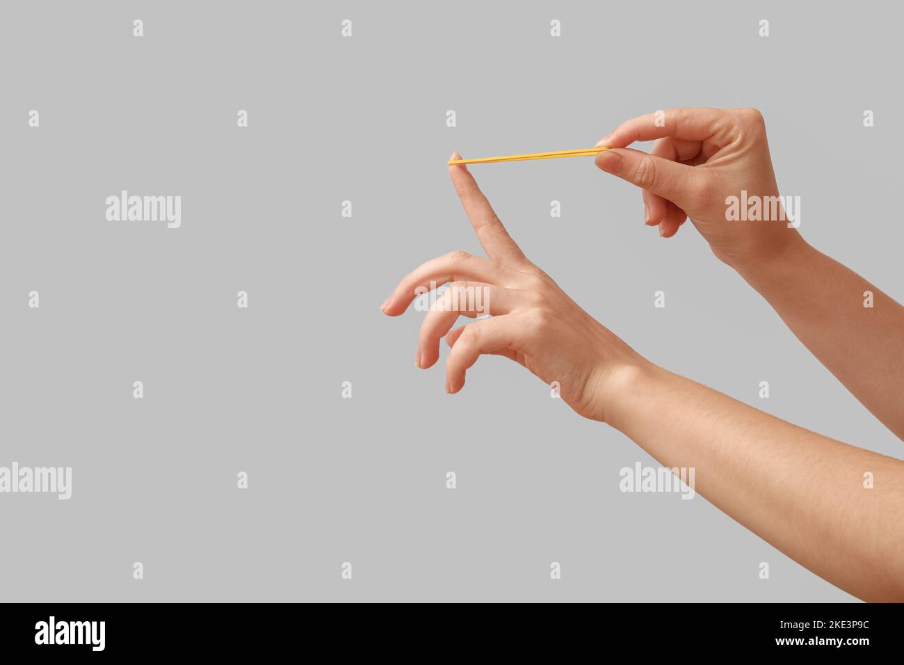 Woman with yellow rubber band on grey background Stock Photo - Alamy