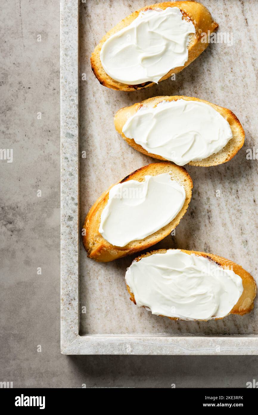 Toasted baguette slices with cream cheese for breakfast on a marble ...