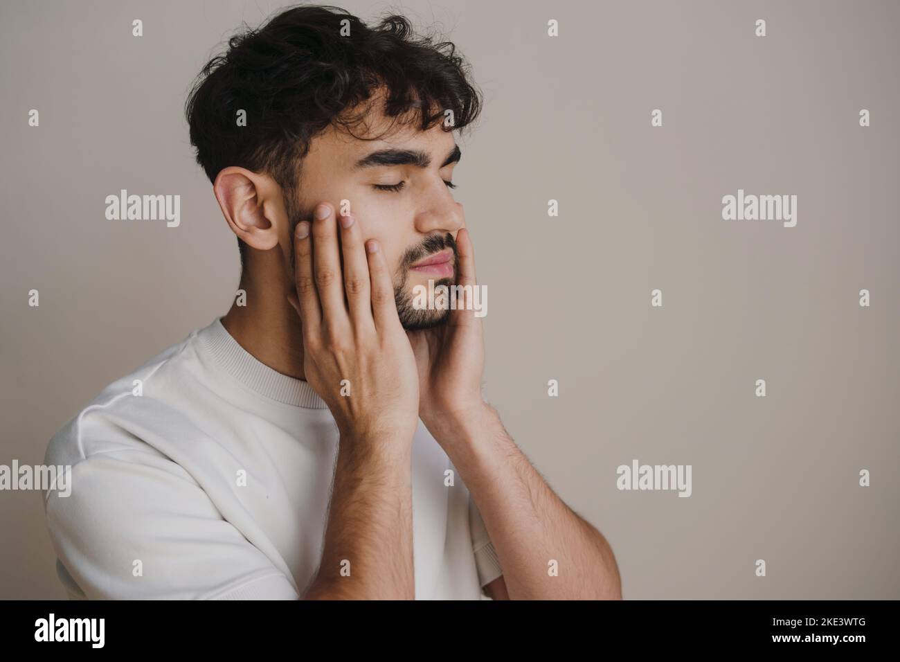 Side view of a confused young man touching his face standing against ...