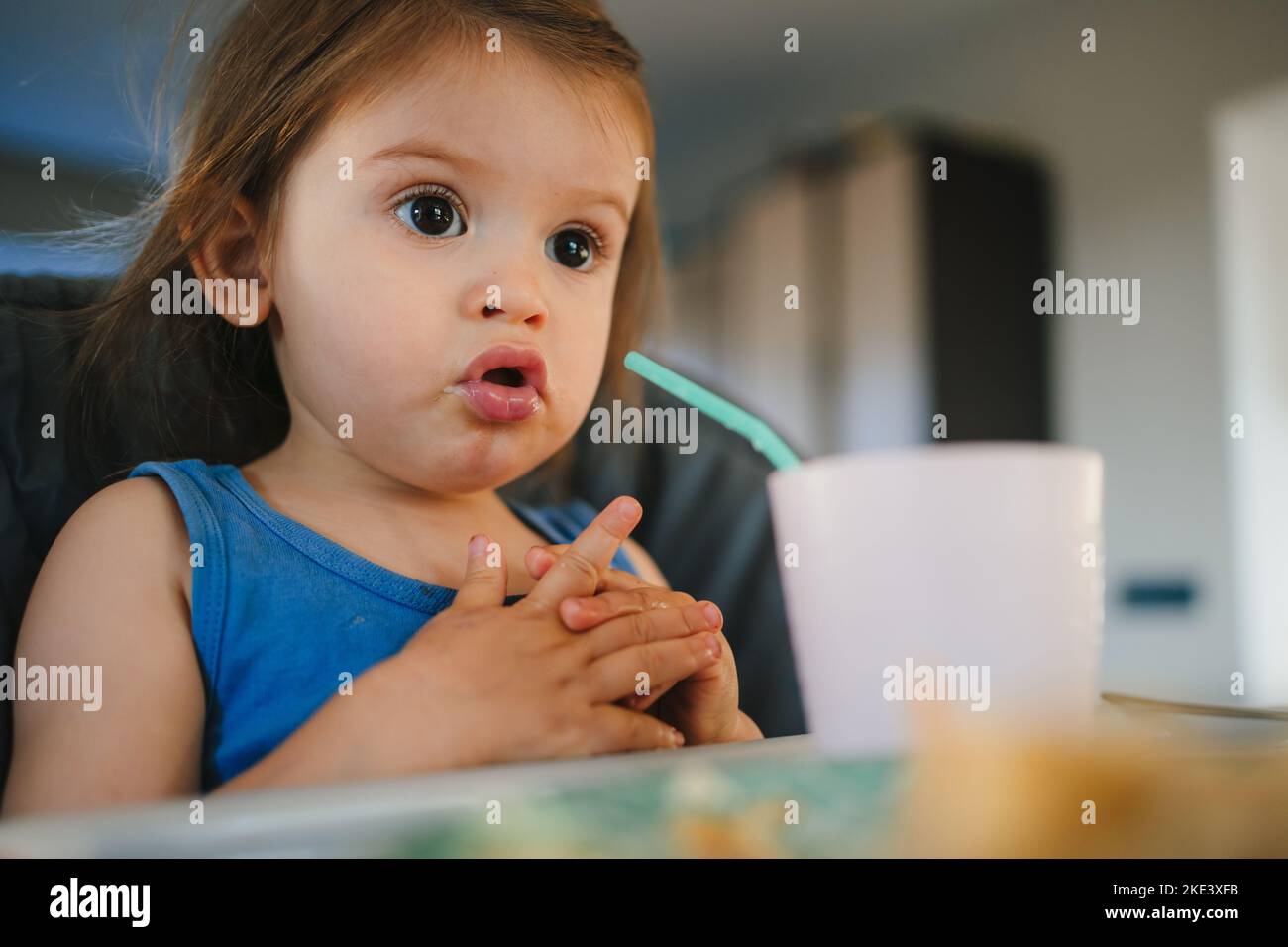 Adorable toddler baby girl sitting on high-chair, eating homemade food ...