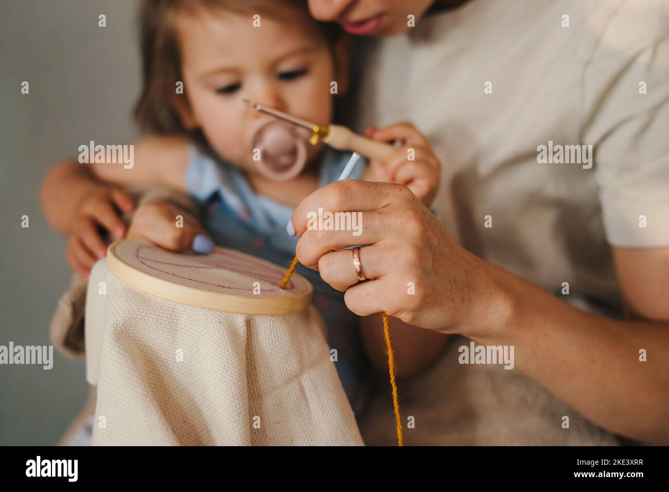 The baby girl watching carefully how her mother embroiders different ...