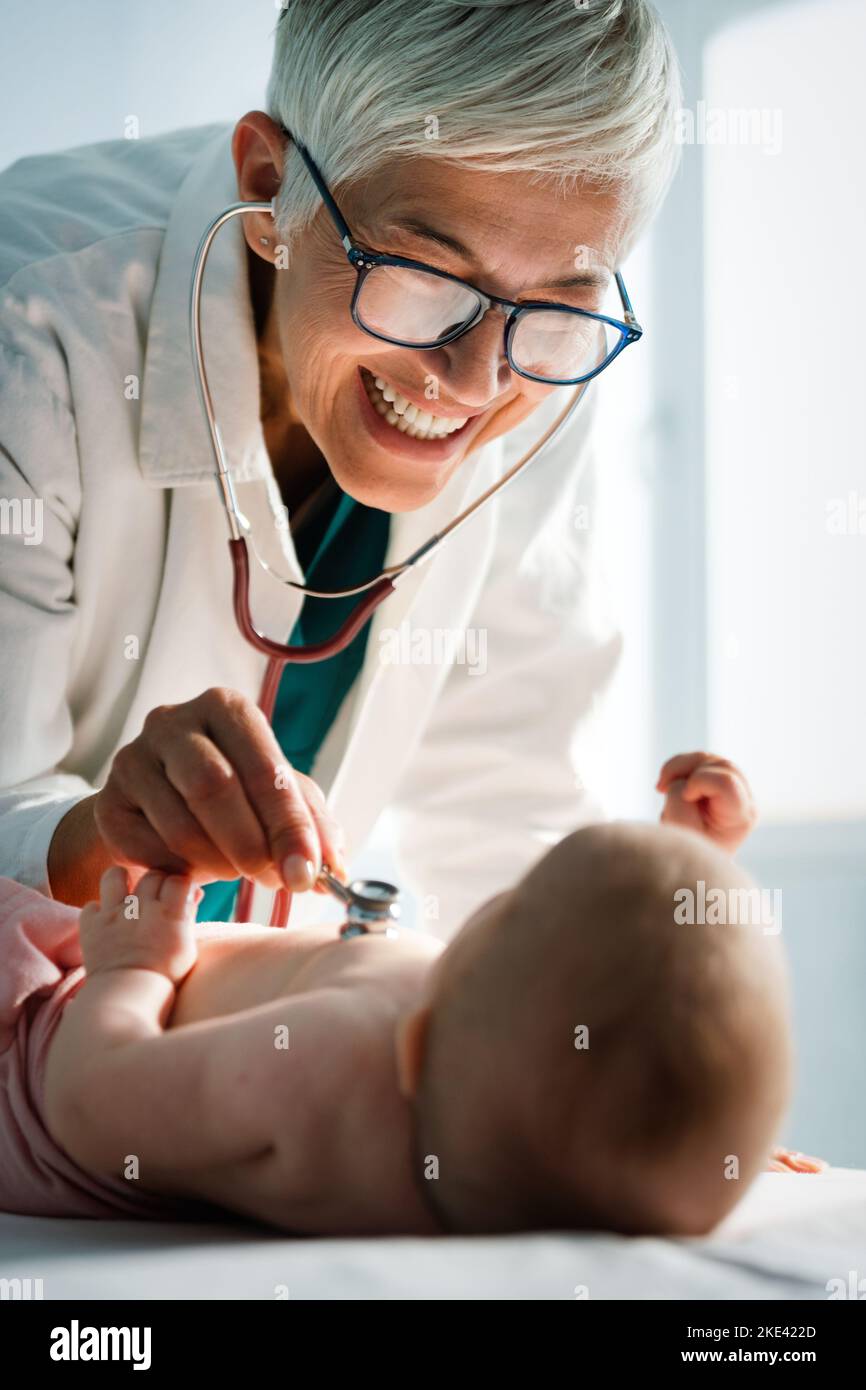 Happy pediatrician doctor with baby checking possible heart defect ...