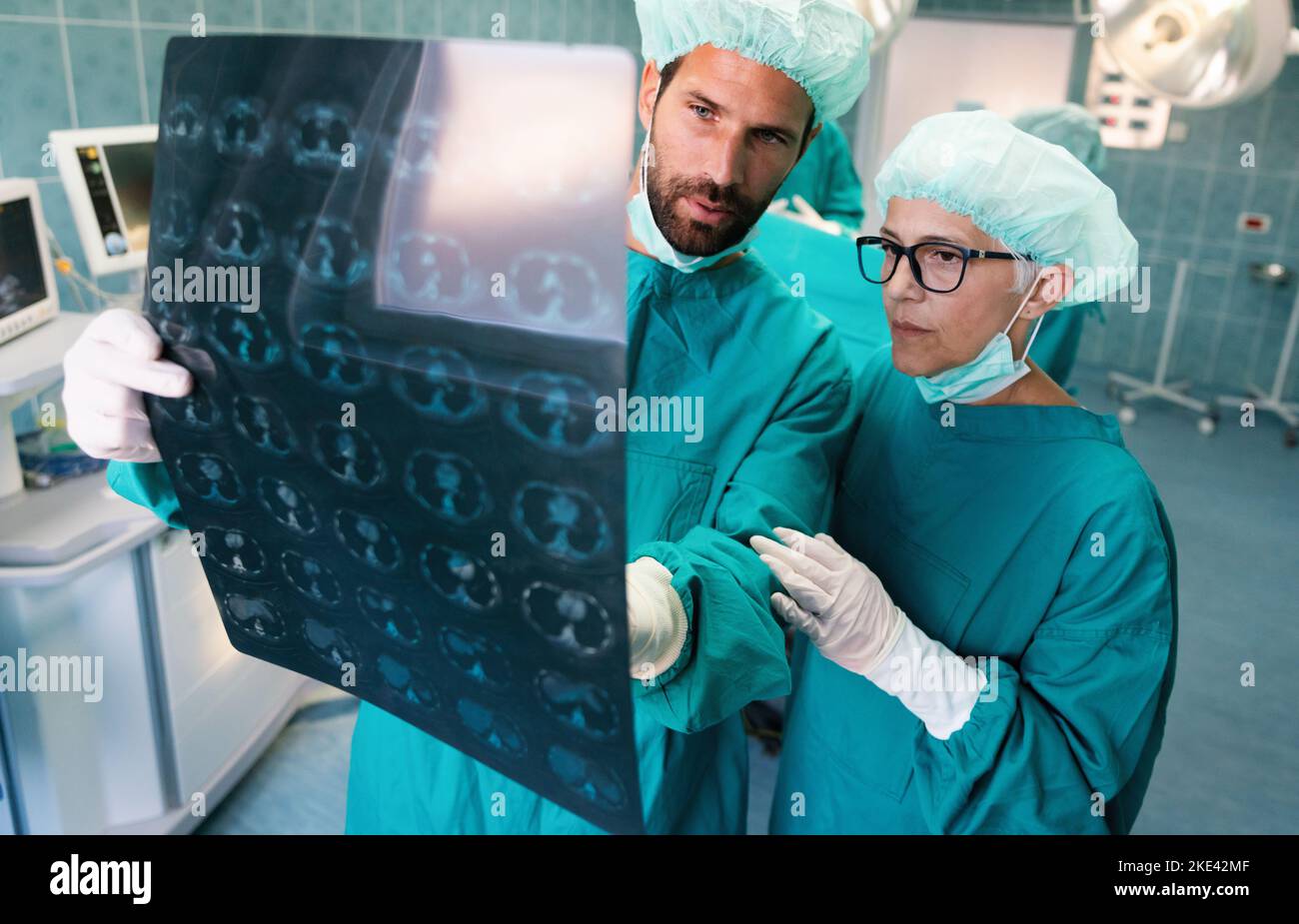 Team of surgeon doctors looking at x-ray film before surgery to set up ...