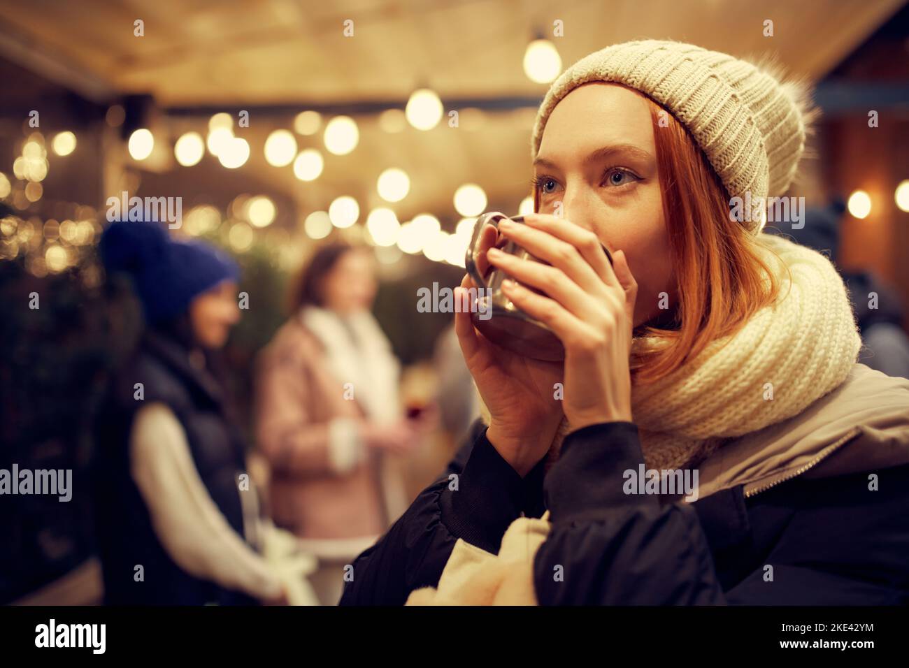 Focus on young smiling beautiful girl in winter clothes drinking hot ...