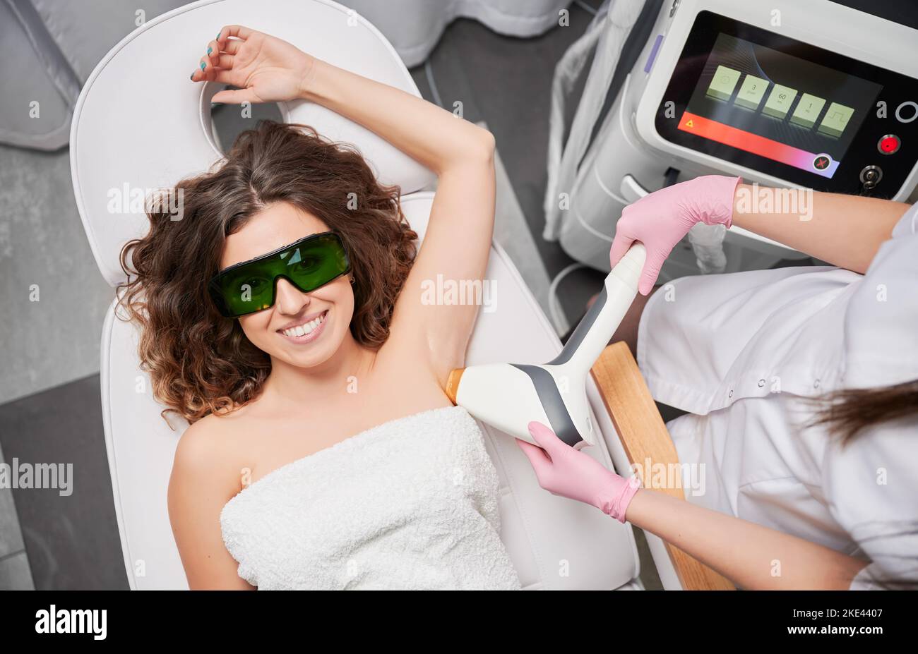 Top view of joyful woman in protective glasses lying on daybed and ...
