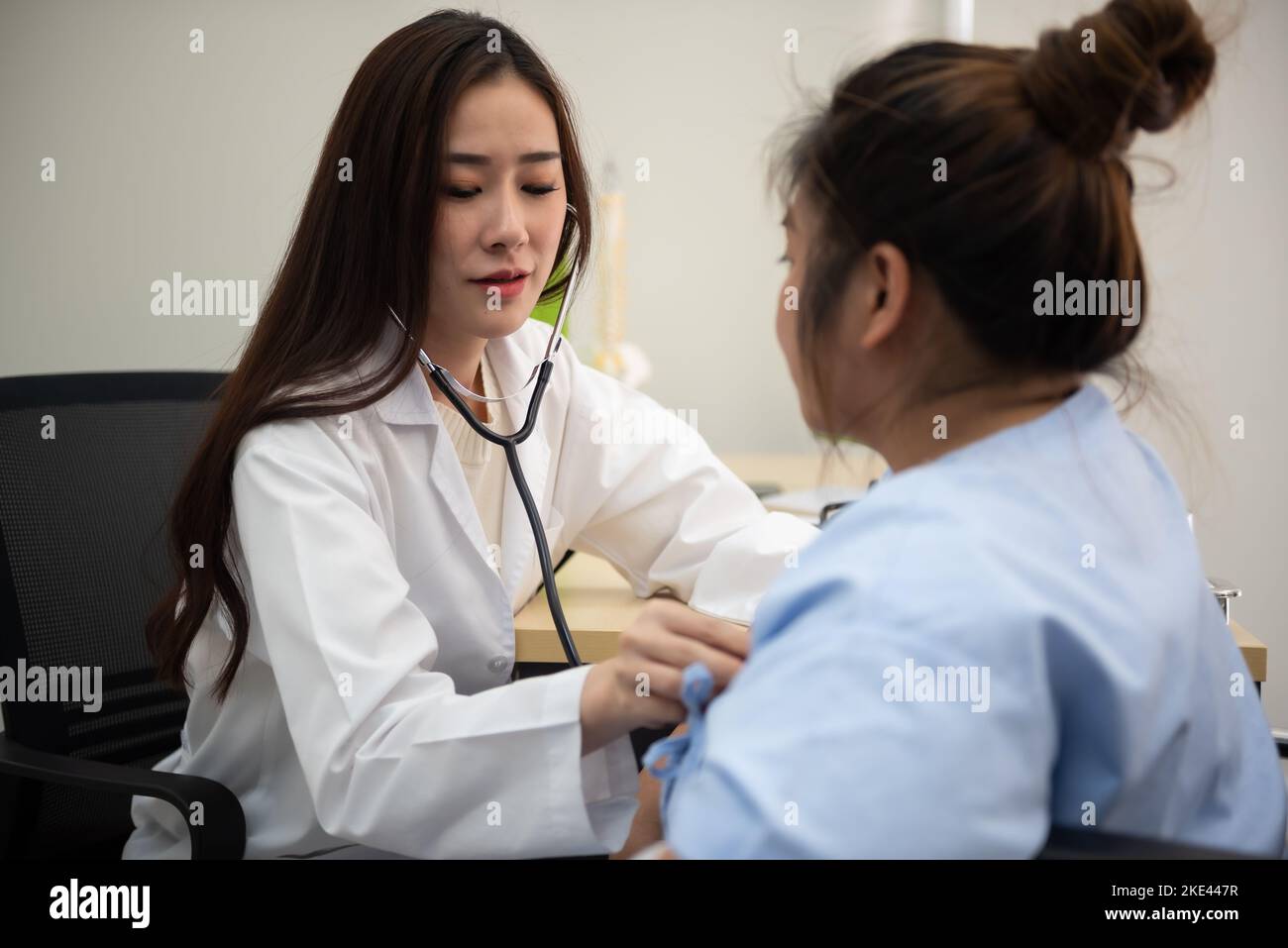 Asian female doctor cardiologist examining fat woman cardiac patient ...