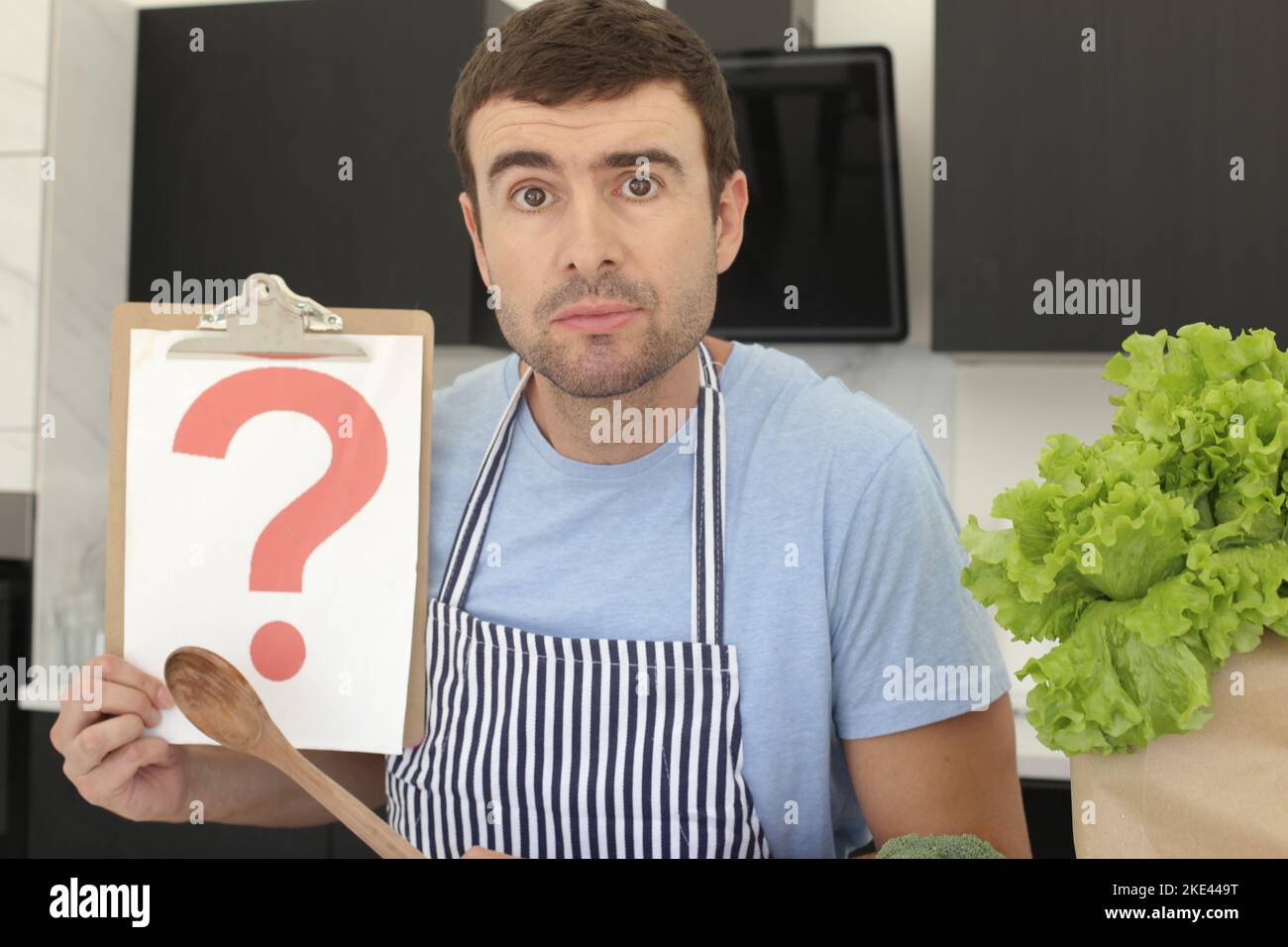 Man holding question mark sign in the kitchen Stock Photo - Alamy