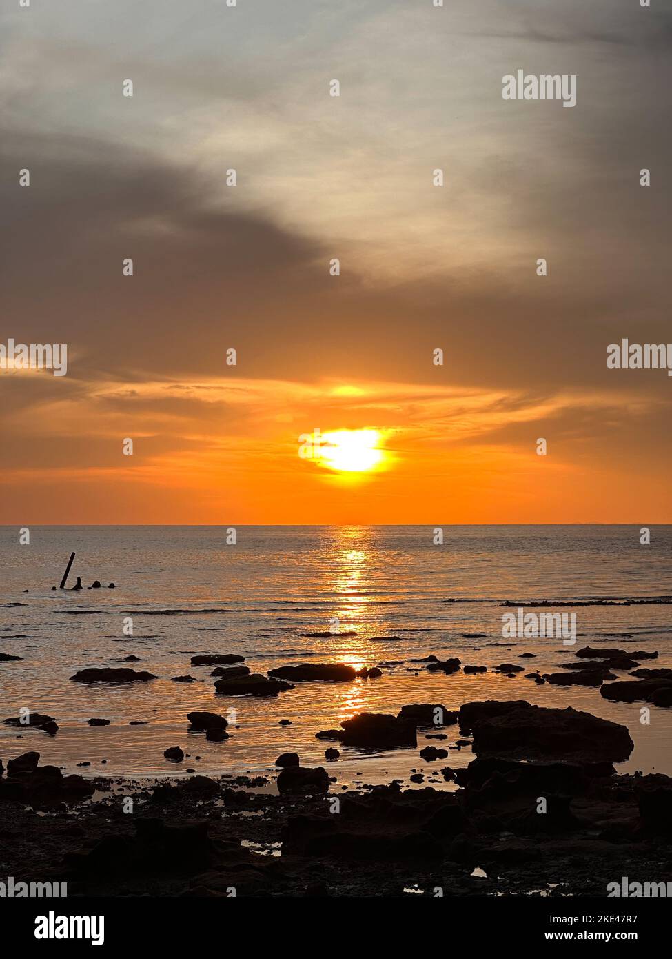 A vertical shot of the beautiful sunset over the ocean in Pulau Aur ...
