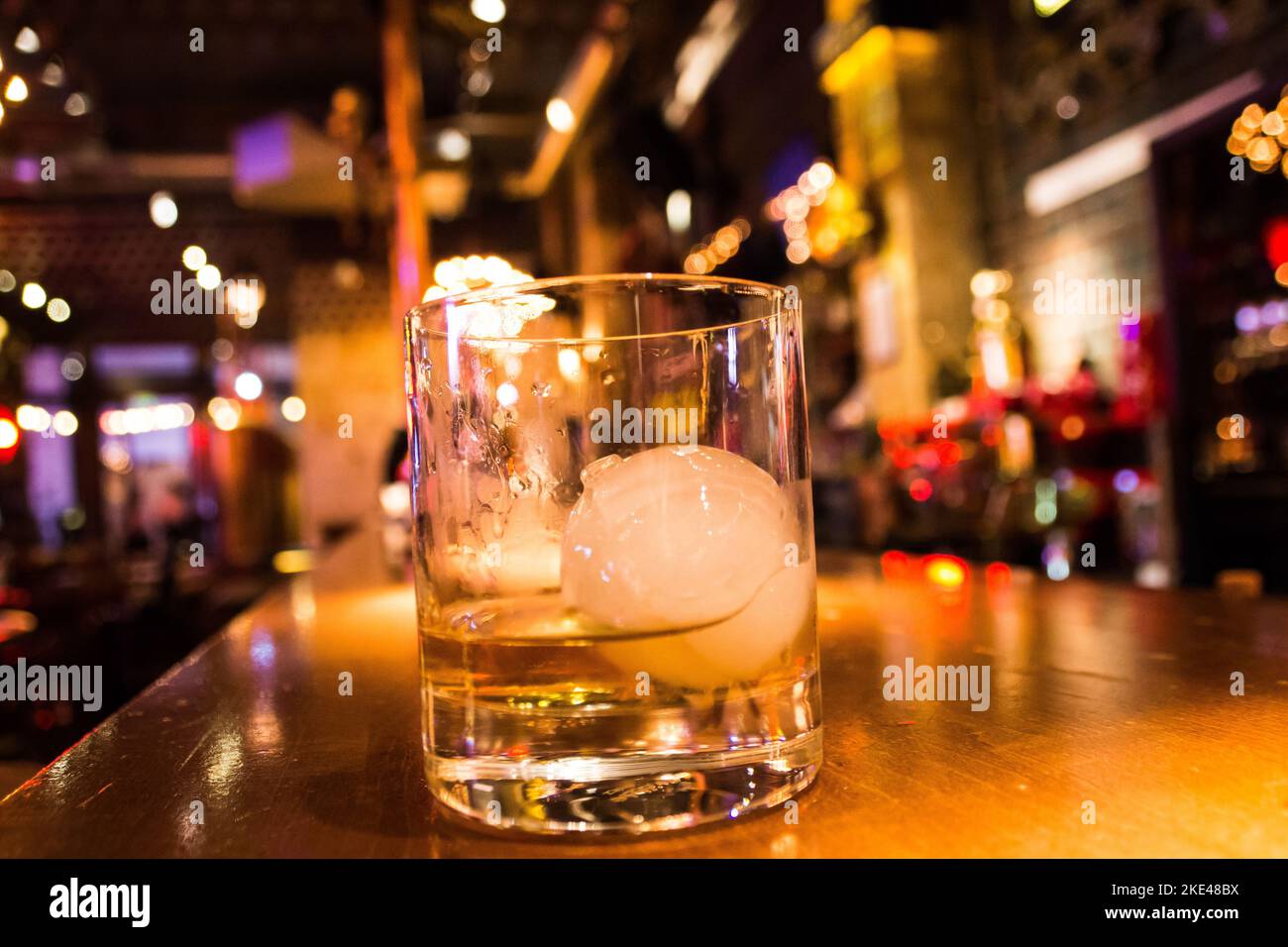 A close-up shot of an ice ball in an alcoholic drink on a bar Stock ...