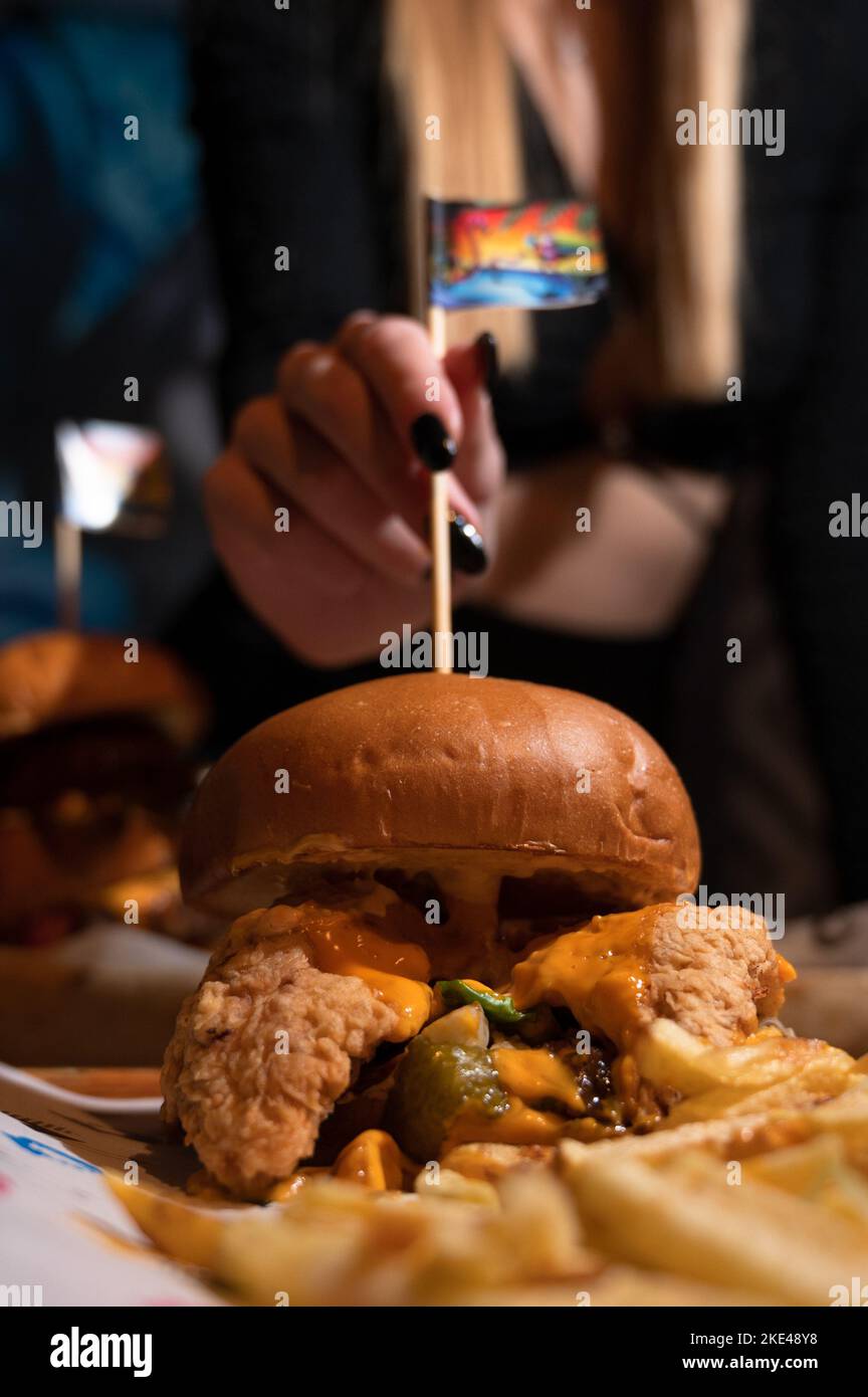 A vertical shot of a chicken burger and a hand pulling out the small ...