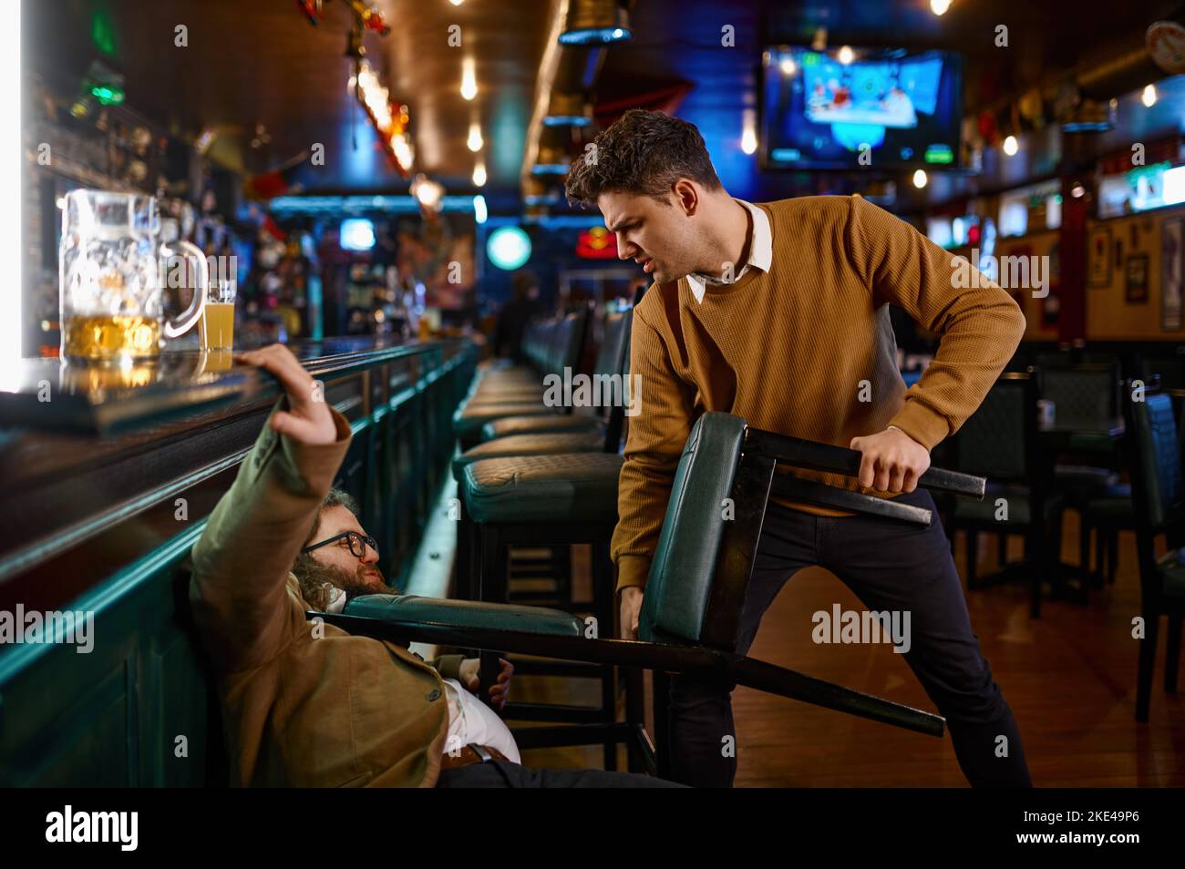Fight in a pub, angry guy pulling friend with chair Stock Photo - Alamy