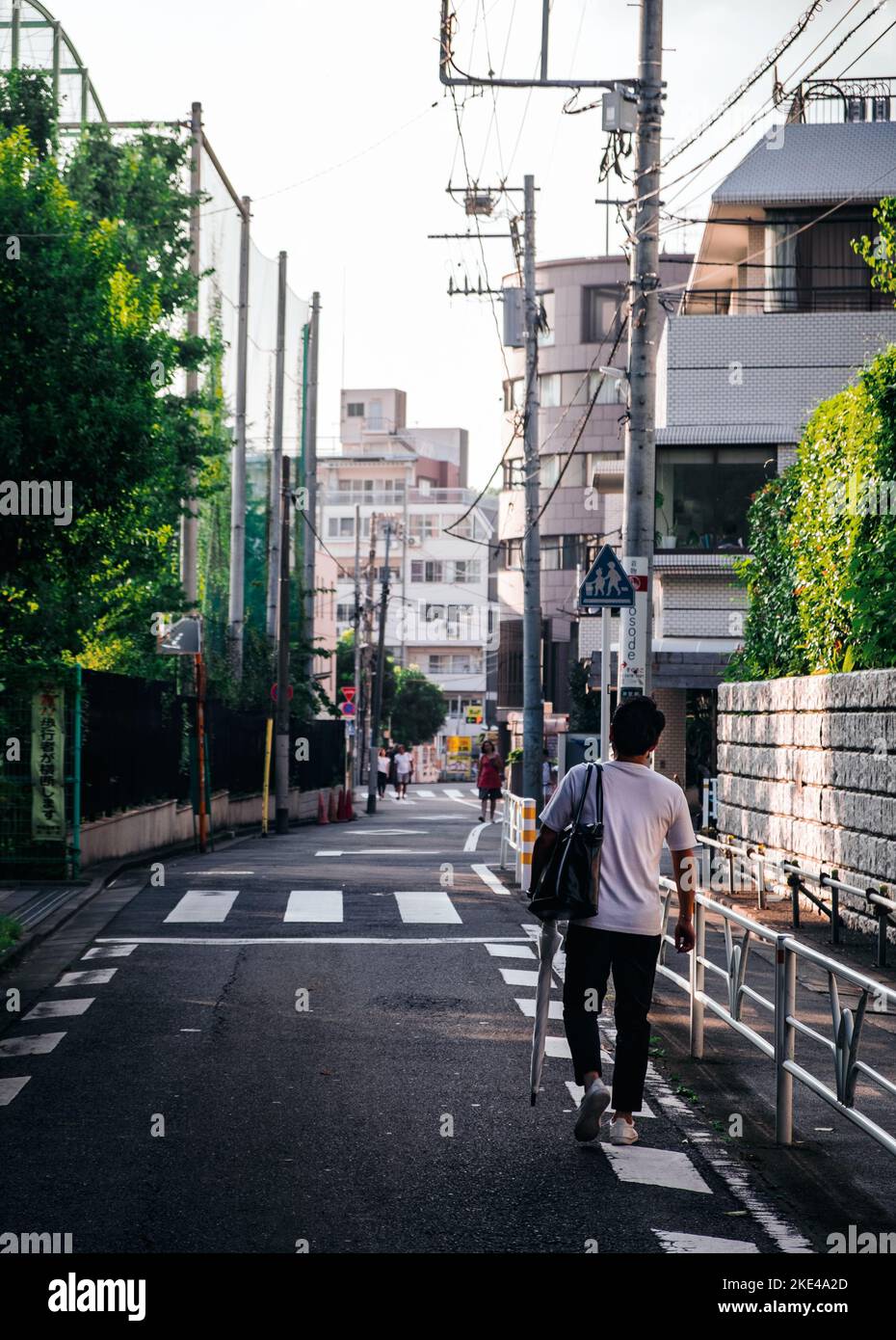 A vertical shot of a man walking on the calm street of Tokyo at evening ...