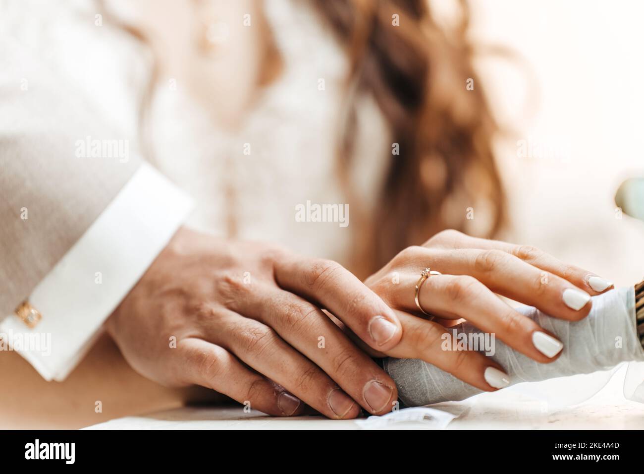 A closeup of the man's hand touching the woman's hand with a ring ...