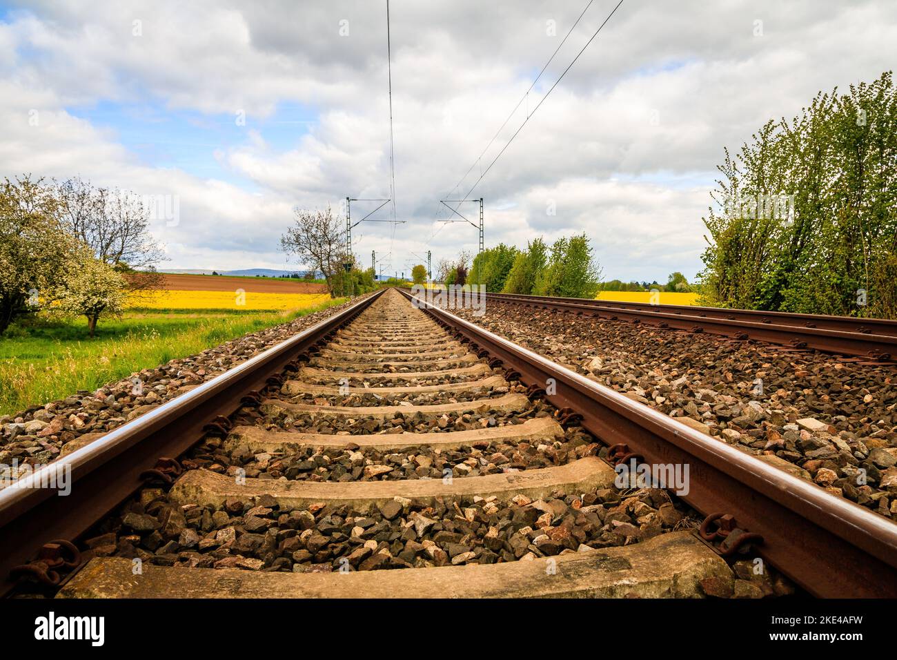 A low-angle shot of a railway in the middle of farm fields under a ...