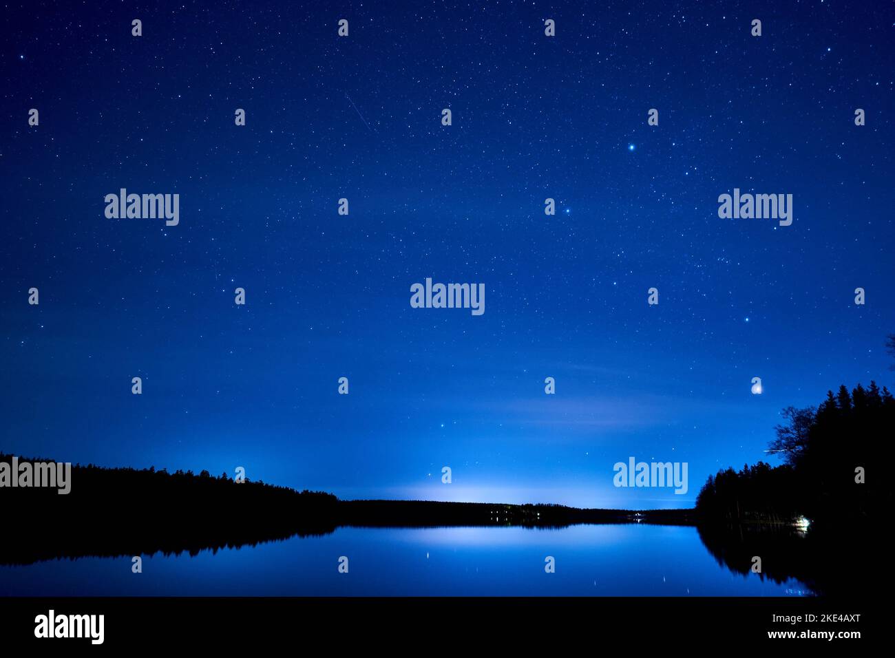 A mesmerizing starry night sky over a pond reflecting on the water ...