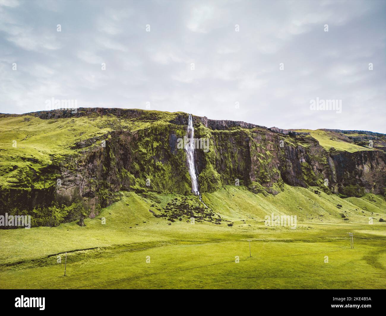 Drifandi waterfall in Iceland, grass field and a cliff with waterfall ...