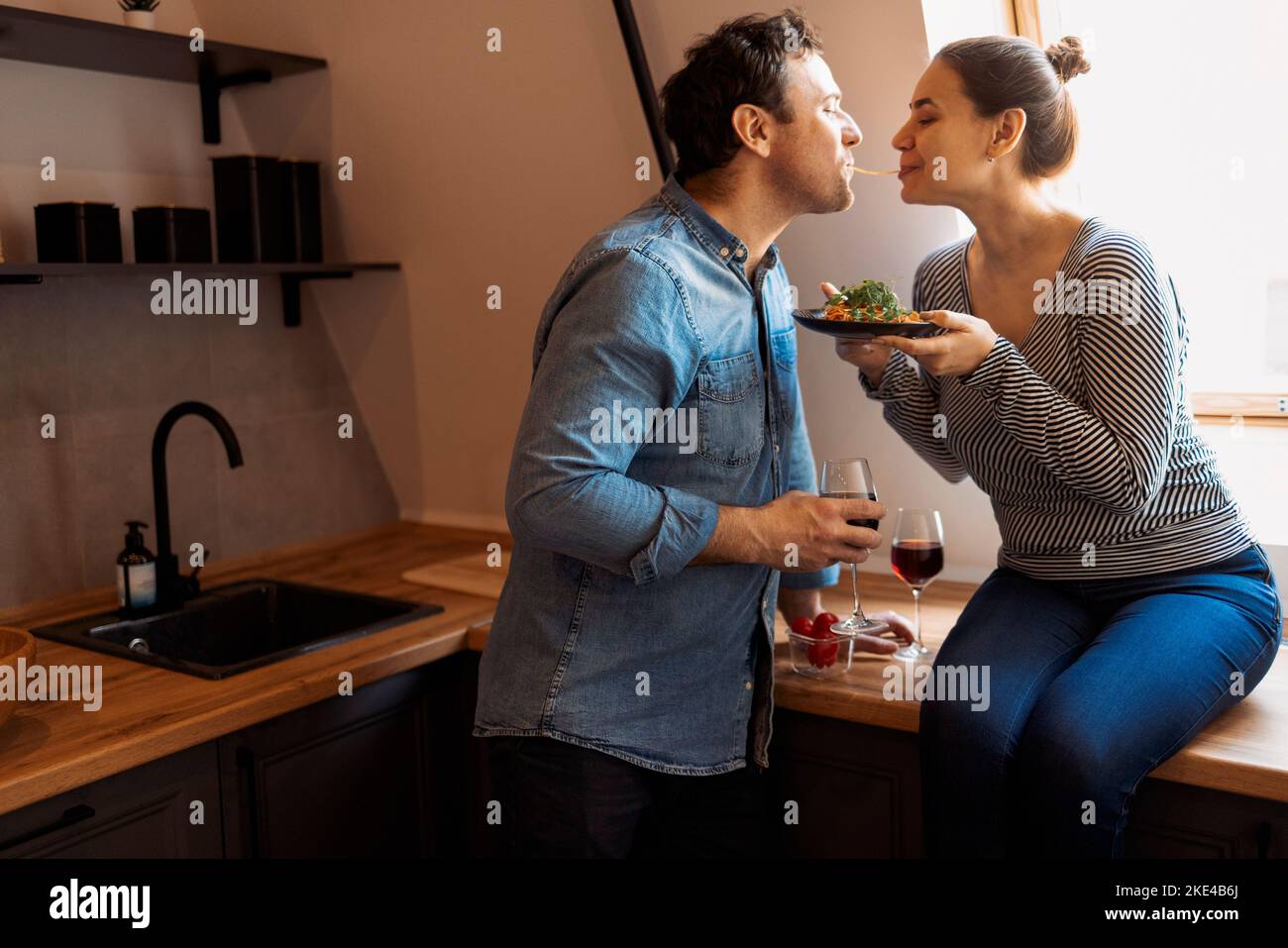 Side view of loving couple eating same spaghetti while having romantic ...
