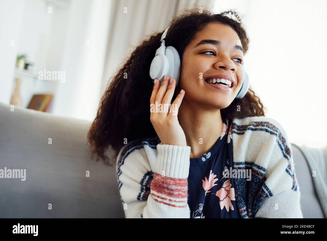 African Millennial Woman In Orange Sweater Wearing White Wireless