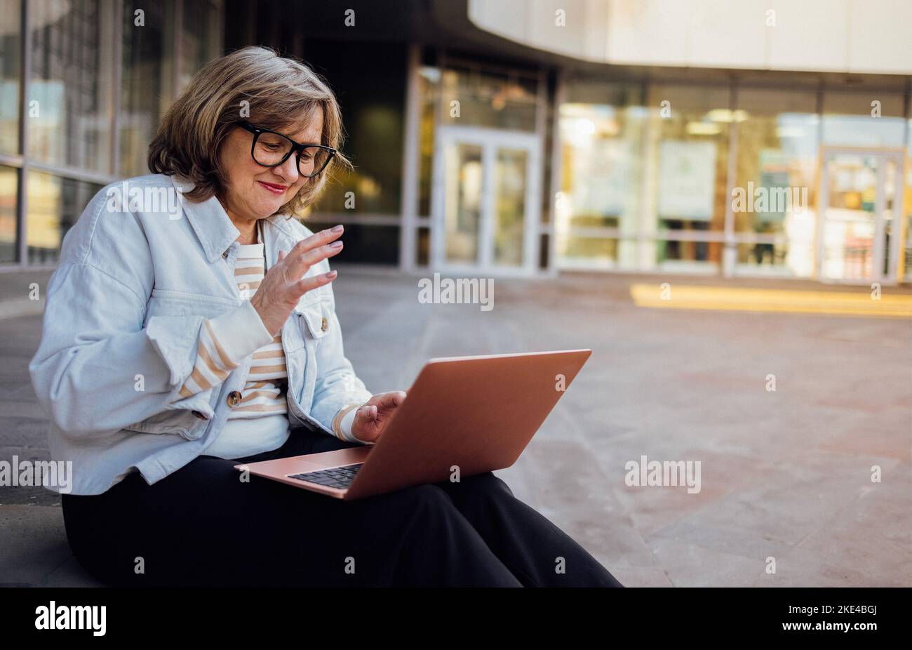 Happy middle aged woman making video call on laptop , waving at screen ...