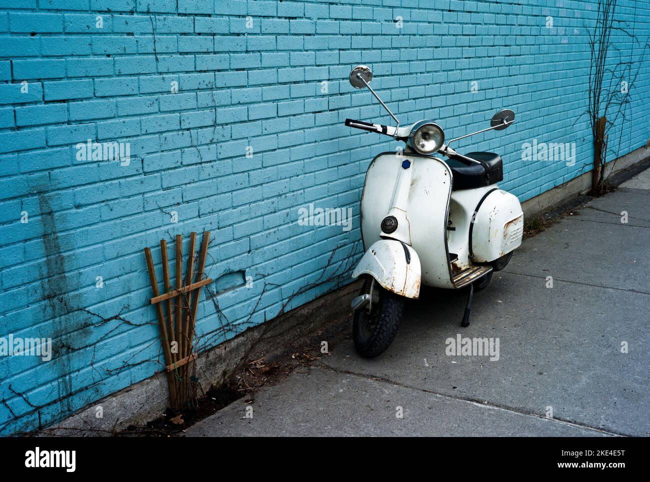 Old-fashioned scooter in front of a blue brick wall in a city street ...