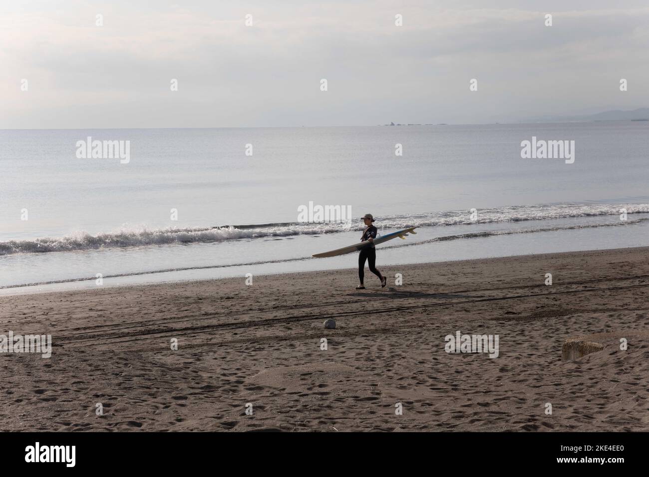 A surfer seen with her board walking on the beach in Enoshima, Enoshima ...