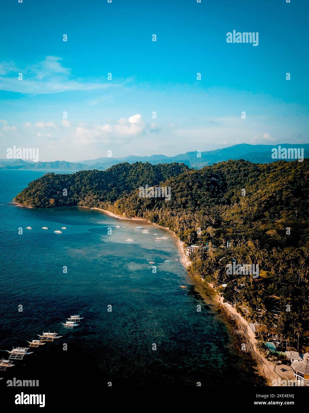 An aerial view of an island and a group of double-outrigger canoes on ...