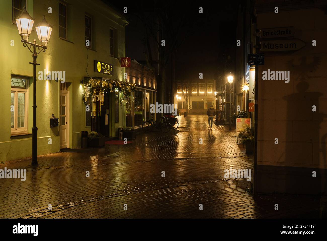 Man walking at night through a foggy historical old town. old lanterns ...